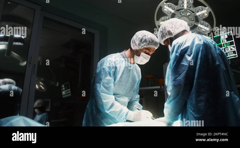 A team of surgeons perform an operation in a bright operating room ...
