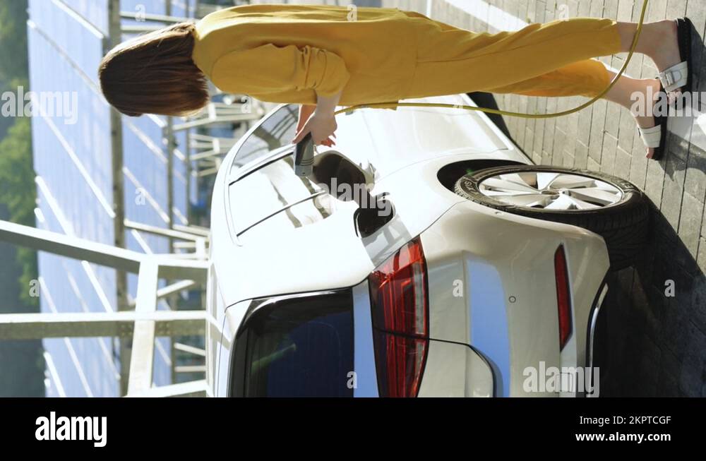 Vertical screen of caucasian female opening an electric car charging ...