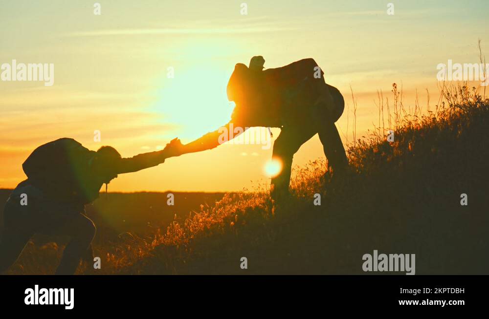 Silhouette two people working in team mountain rock climbing. Helping ...