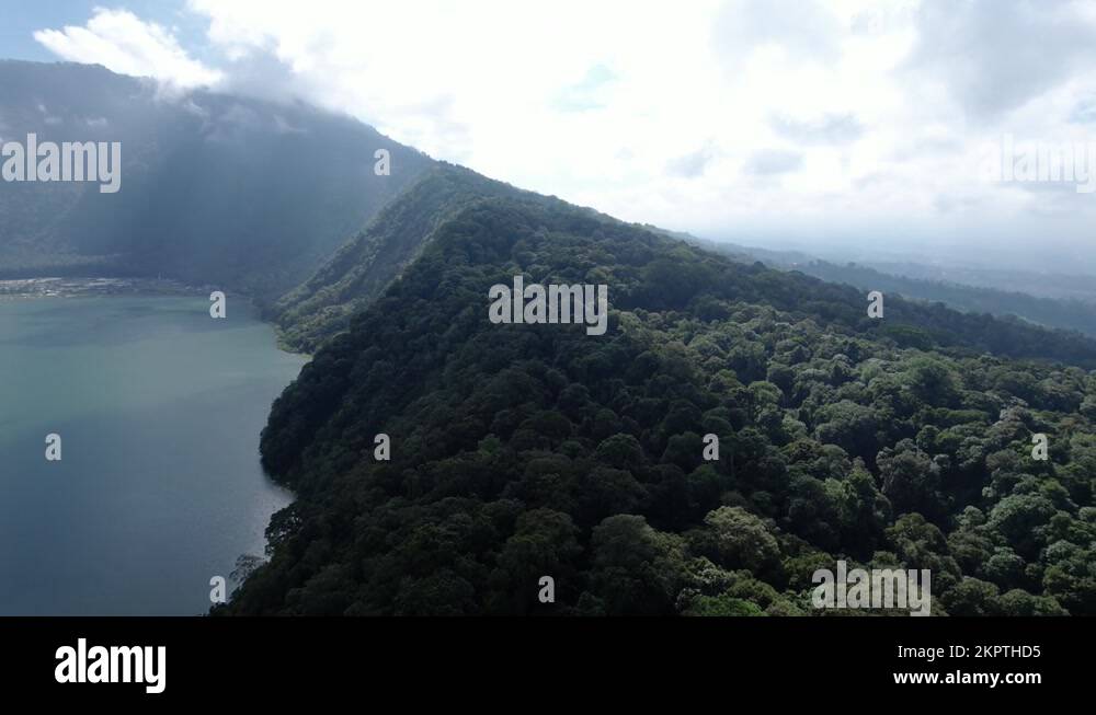 Forested crater edge of big old volcano, aerial shot, Bratan lake seen ...