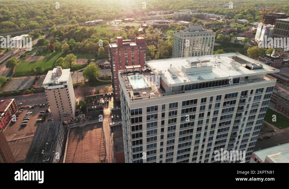 Flyover above high rise apartment building at sunset, swimming pool on ...