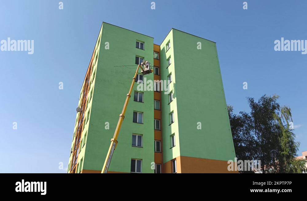 Worker using a crane and cleaning facade of the prefab house which was ...