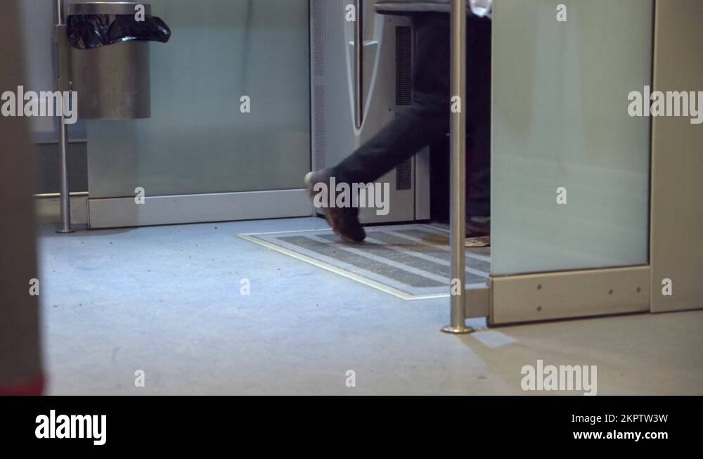 Train door opens on transit platform and passenger departs, low angle ...