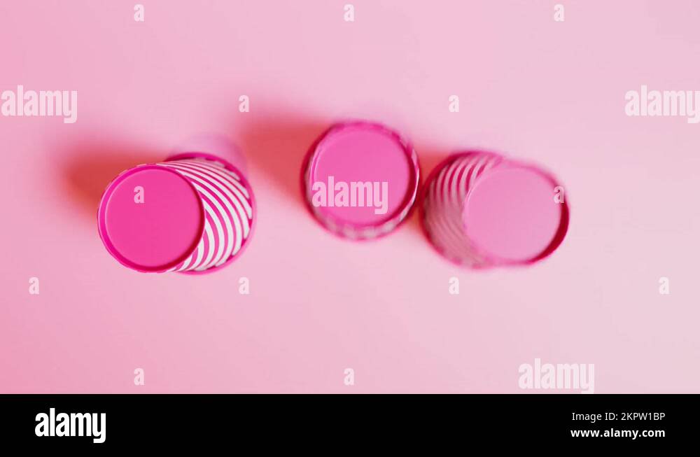 3 Cups and a ball game. Try to guess where a ball is. Pink background ...