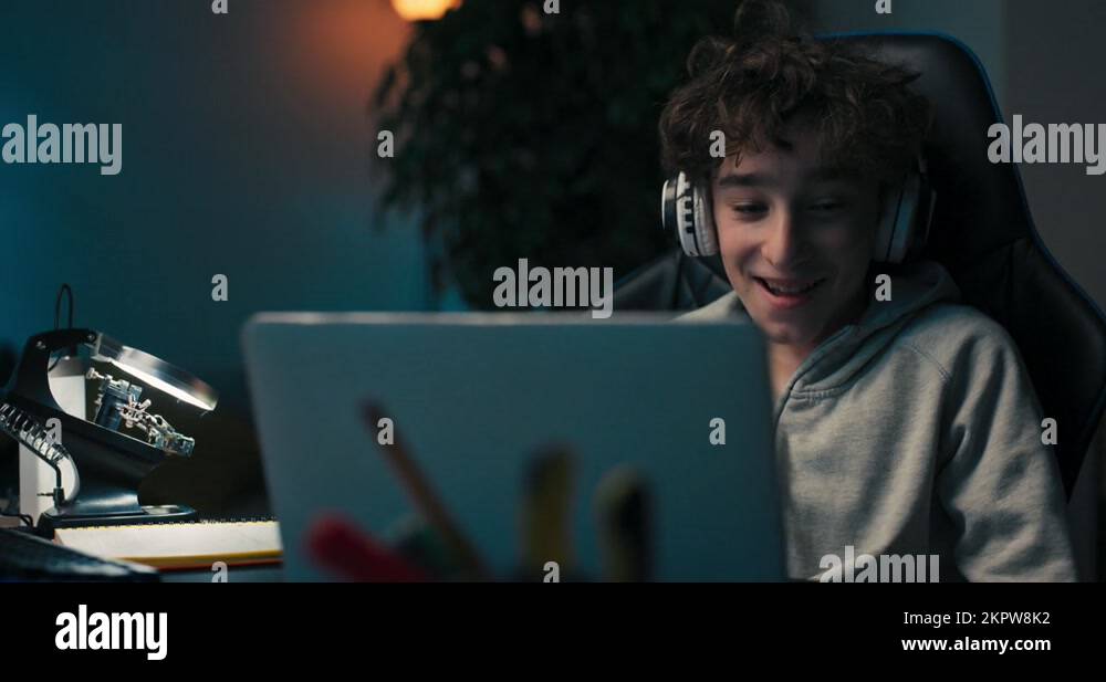 The boy has remote school activities in room, sitting comfortably in ...