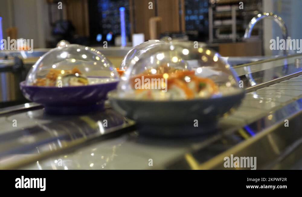 Japanese restaurant with sushi and rolls moving on plates on rotating ...