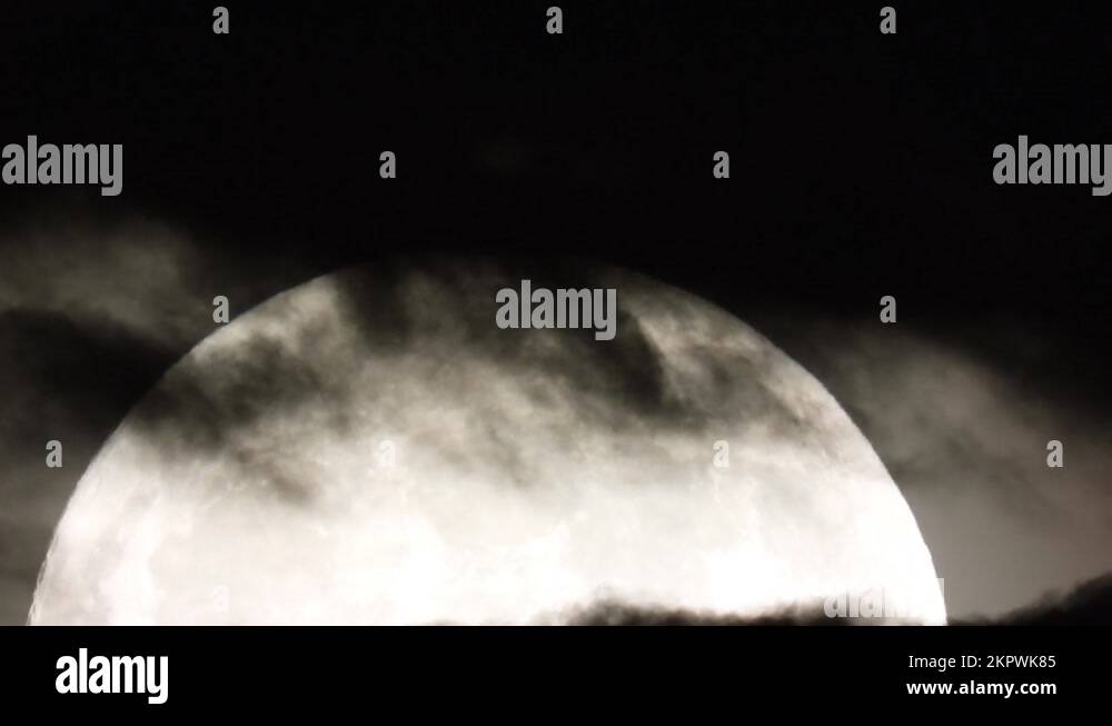 An eerie full moon rising from behind a hill vanishes behind a dark ...