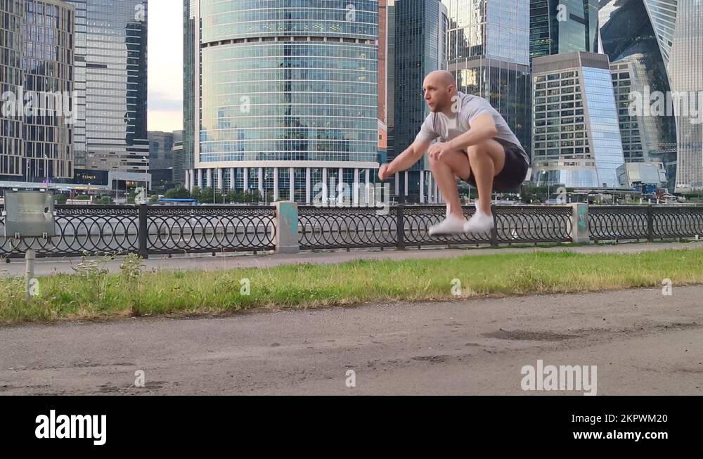 Warm-up of a bald, young man. Jumping with raising the knee to the ...