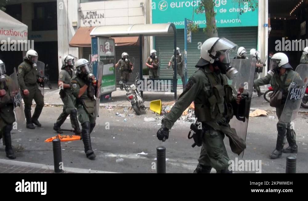 Greek riot police carrying shields, wear helmets and gas masks charge ...