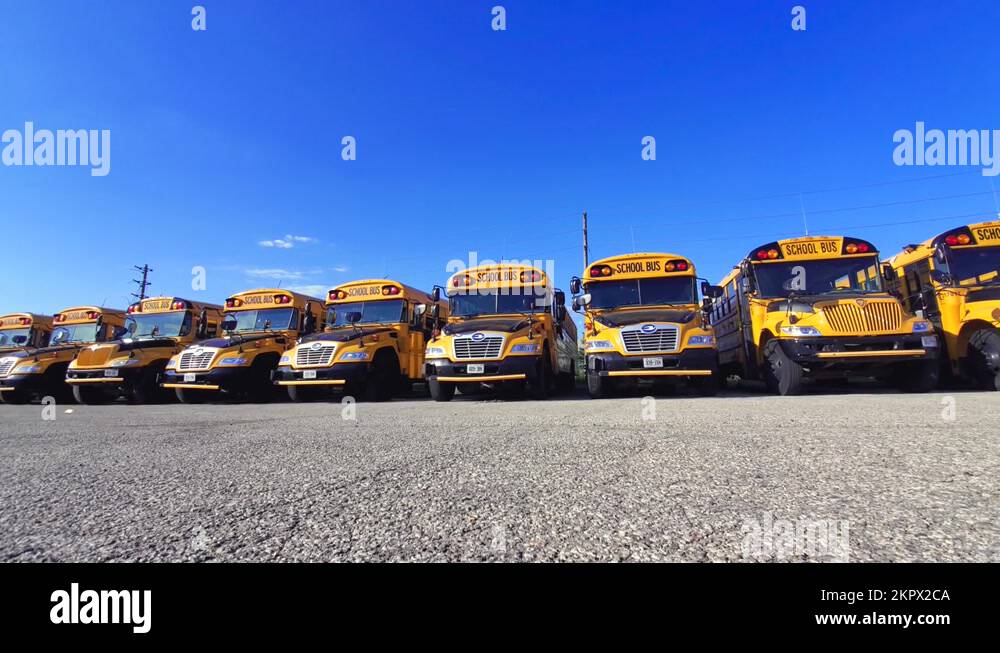 Row of yellow school buses lined up at parking lot ready to take kids ...