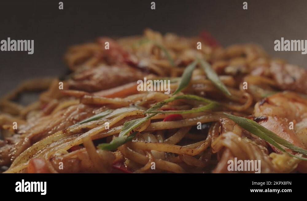 Chinese noodles, wok noodles with chicken. Process of cooking close up ...