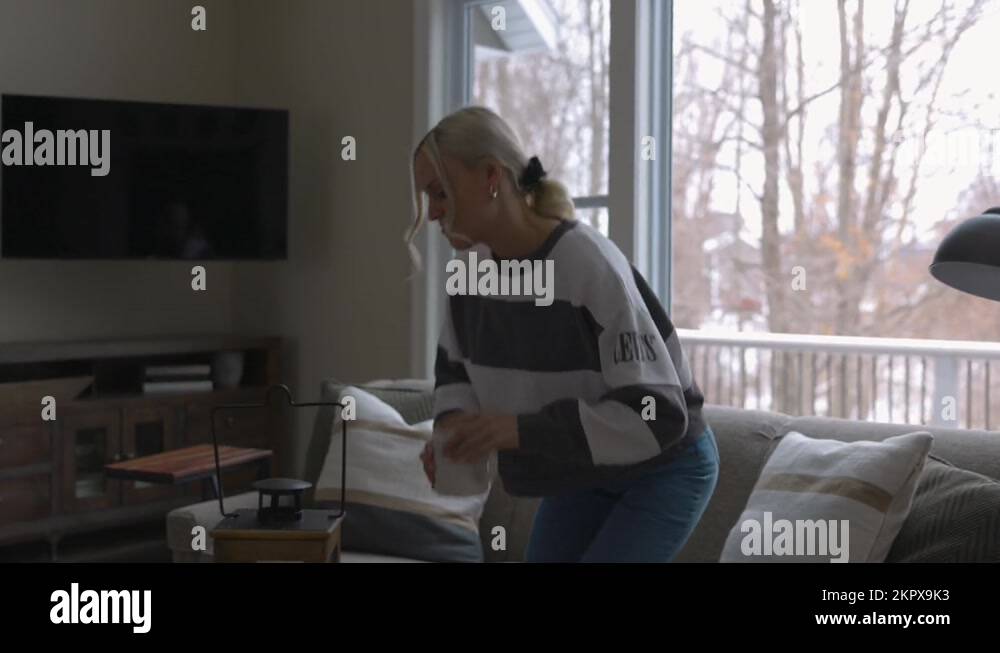 woman walking to the couch to lay down and scroll through tablet while ...