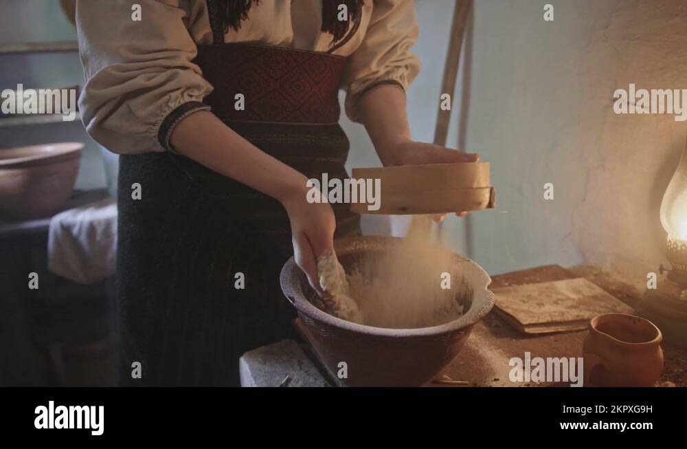 Slavic woman sieving flour into dough. Tilt up and down view of female ...