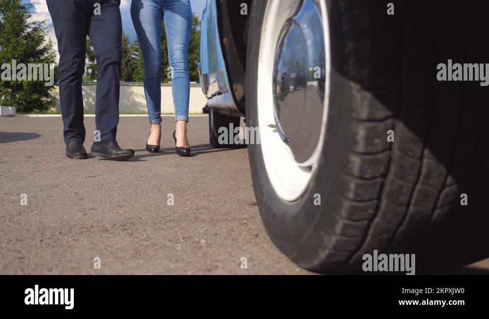 Legs of girl getting into retro auto. Man opens and holds door of ...