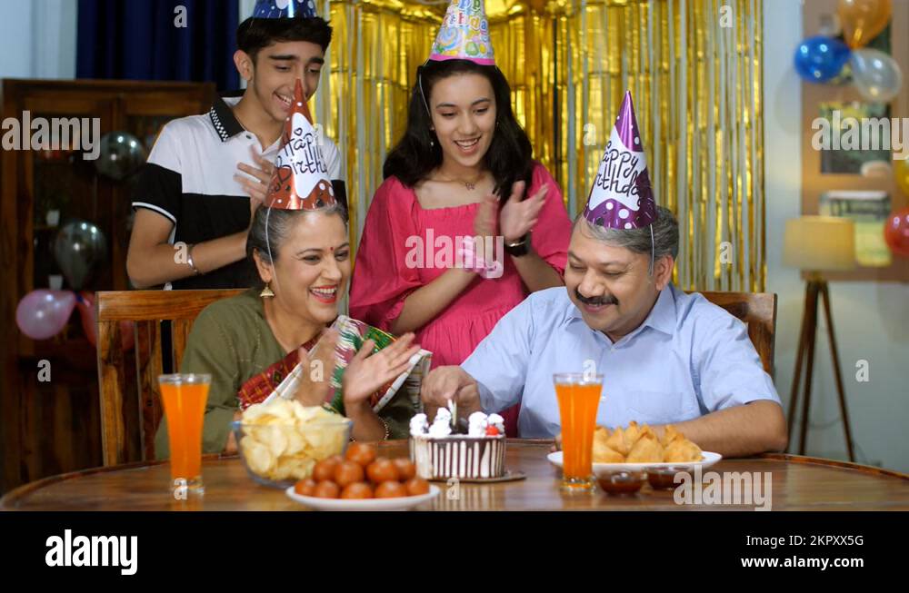 A middle-aged man in his late forties cutting a birthday cake with his ...