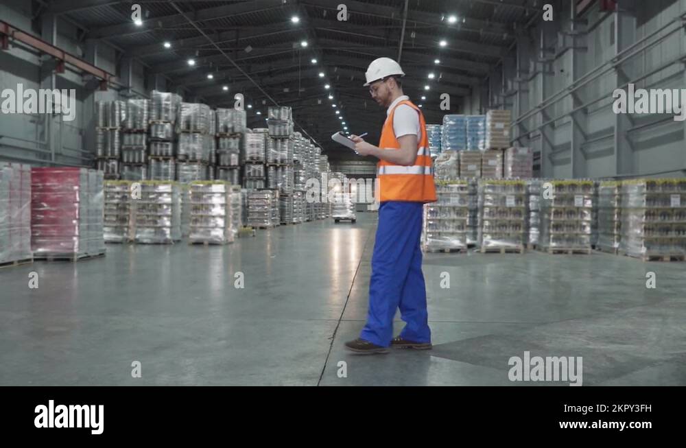 Labourer counting the goods at the storage using a paper inventory ...