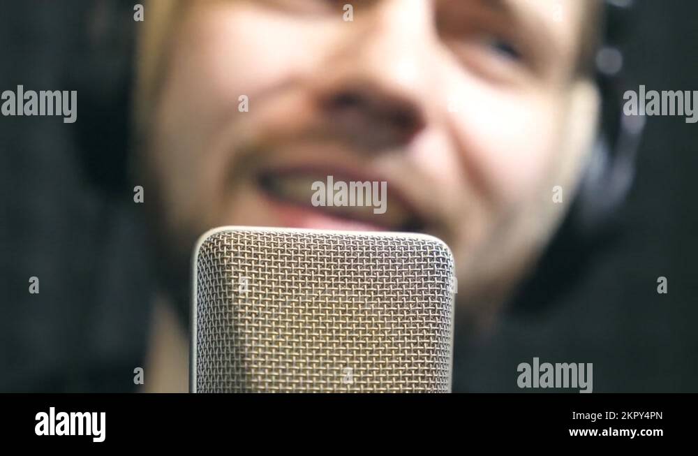 Male singer in headphones singing song into the microphone at sound ...