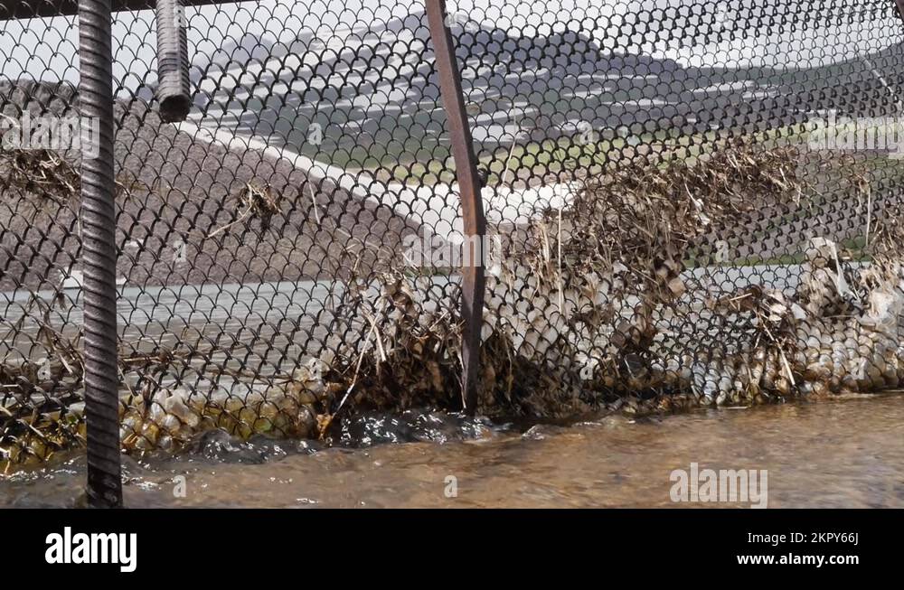 A metal mesh is stretched over a dam in a mountain lake and serves as a ...
