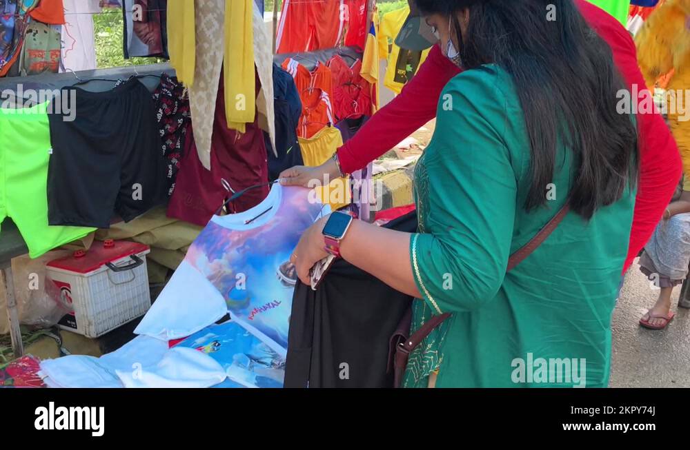 A lady shopkeeper displays clothes with lord shiva prints for sale to ...