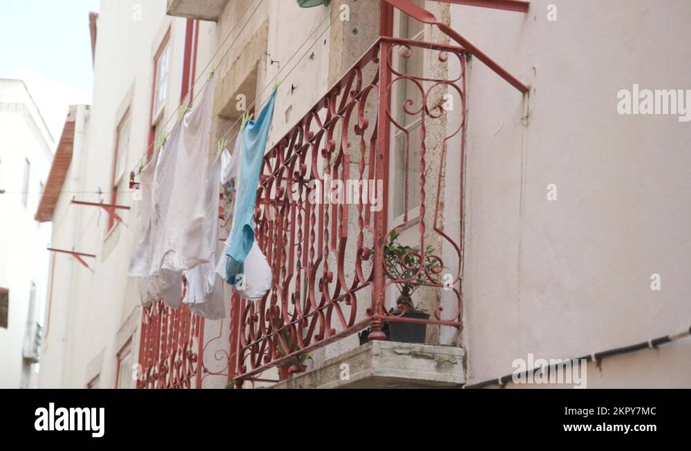Clothes on a clothesline hanging from a balcony window in Lisbon ...