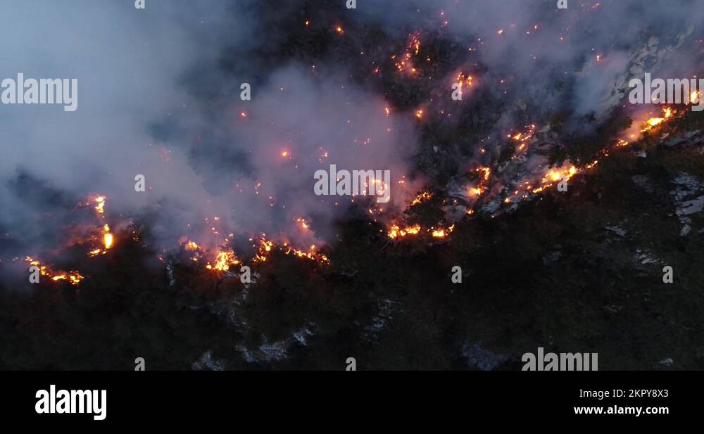 Aerial panoramic view of a forest fire at night, heavy smoke causes air ...