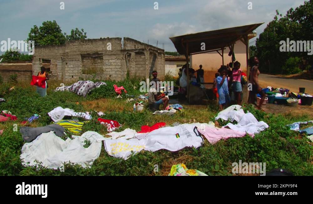 Women washing clothing at a public water source and drying them on ...