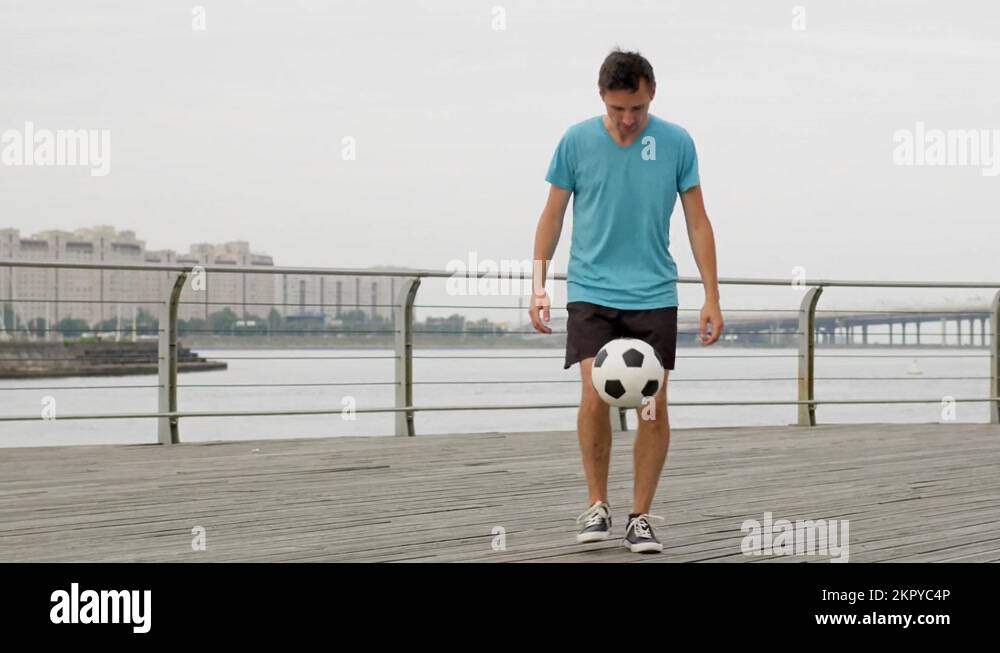 Man soccer player is kicking bouncing a ball performing tricks on ...