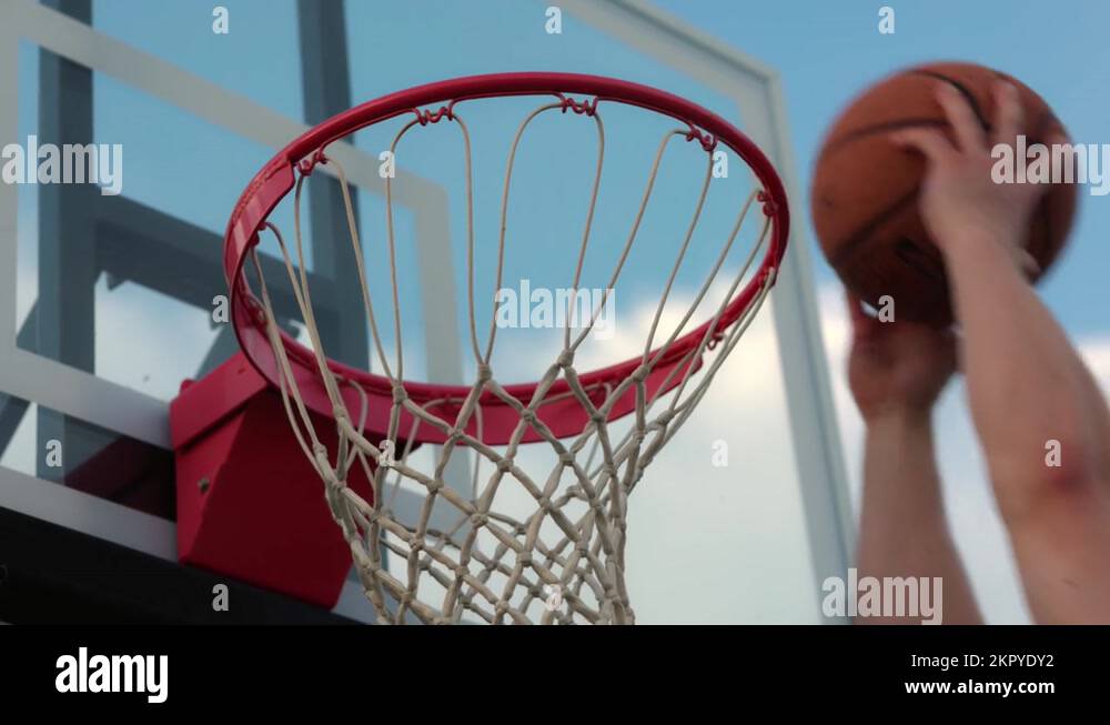 man dunking on a new basketball net and holding onto the ball rim after ...