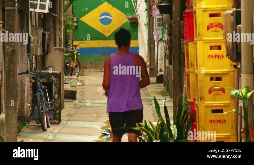 Man walks down an ally in a Rio de Janeiro favela in Brazil - flag ...