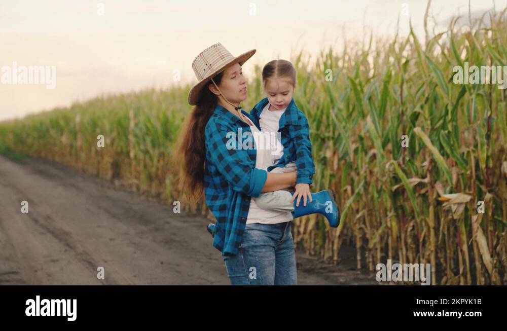 Farmer woman works in cornfield with his little daughter. Farmer Mother ...