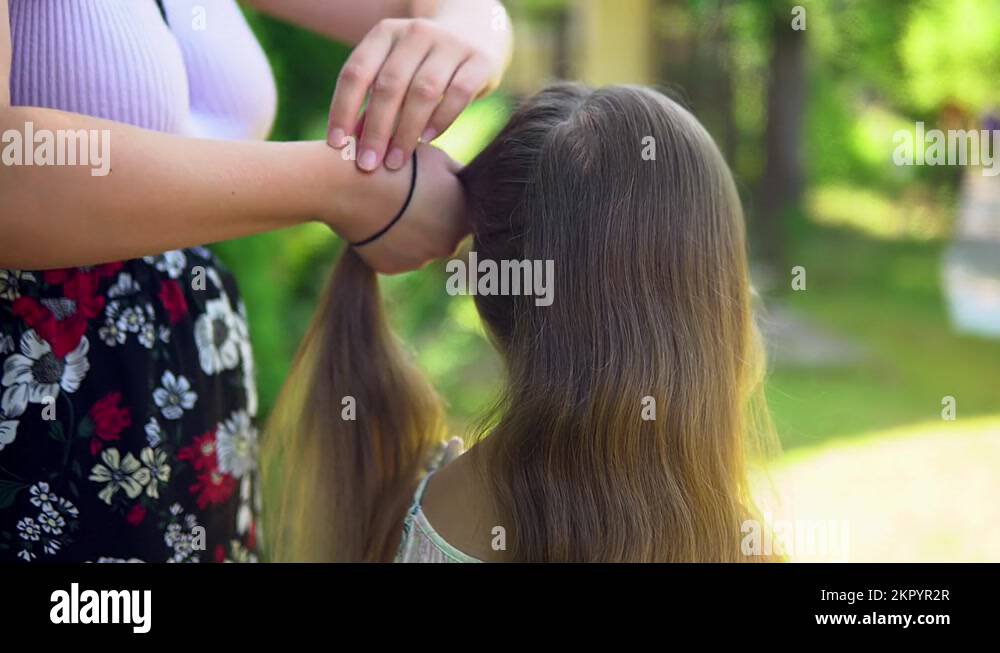 Mom in the yard weaves braids to a little girl wit Stock Video Footage ...