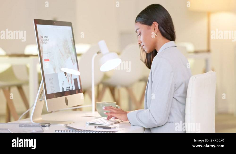 Female web designer typing on a computer and comparing graphic notes to ...