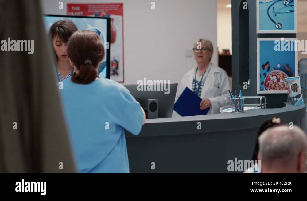 Medical staff and secretary talking at hospital reception desk Stock ...