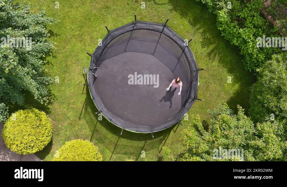 Aerial top-down view of a teenage girl jumping on trampoline in a ...