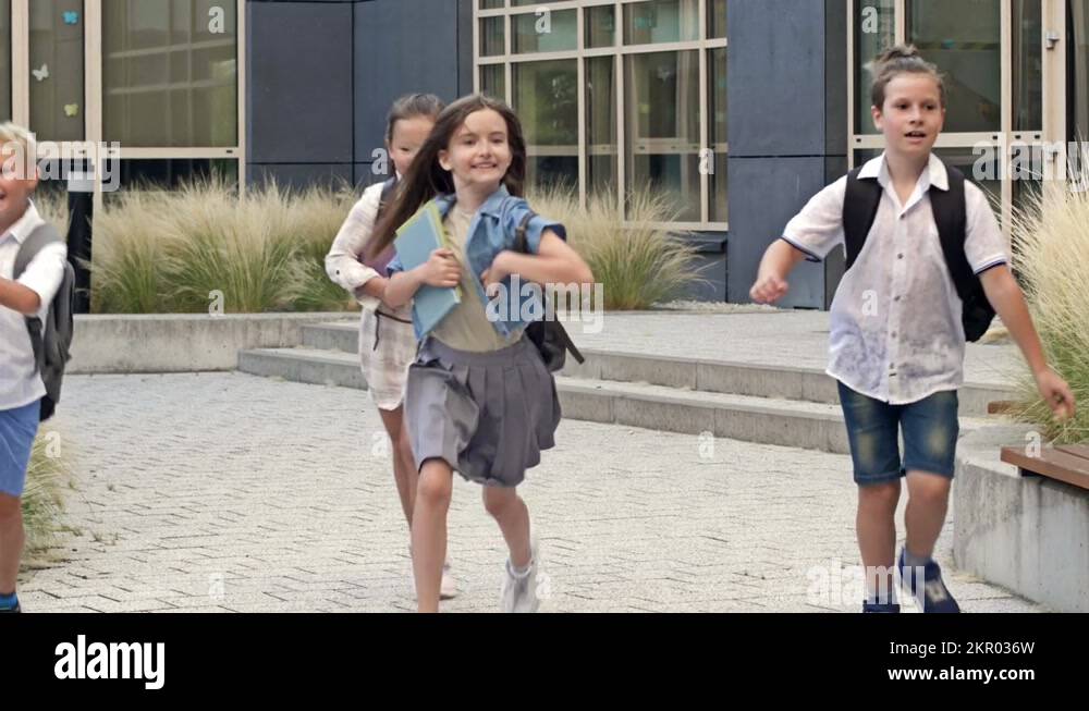 Group of elementary school students joyfully run out of the school ...