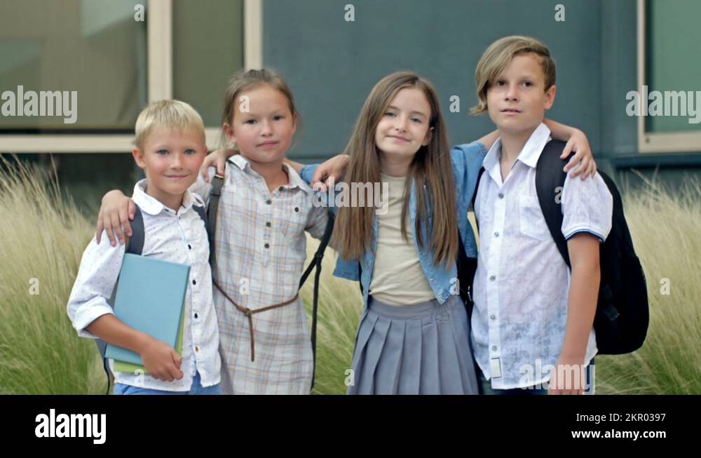 Four friends, elementary school students, stand in an embrace in the ...