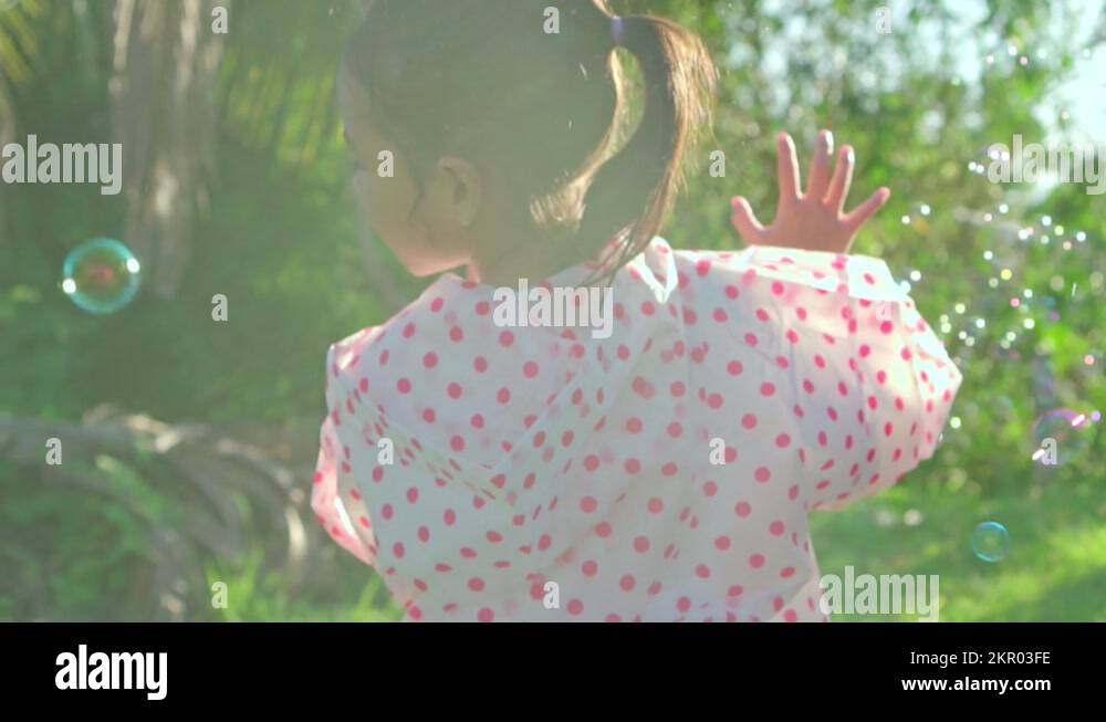 Asian girls in rainwear is playing air bubble from spray gun with her ...