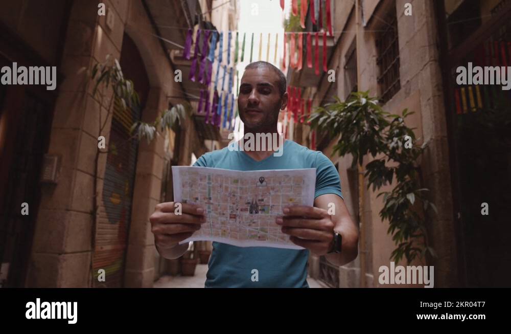 Happy male tourist maps user walking in old town alley an using a map ...