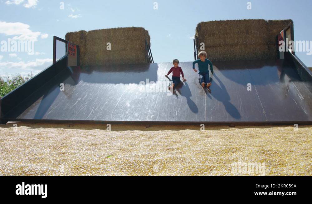 Two boys slide into huge pile of hardened corn kernels in slow motion ...