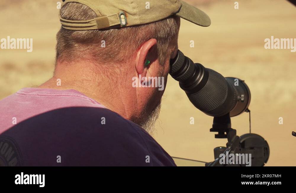 Hunter Scout looking through spotter scope at the shooting range ...