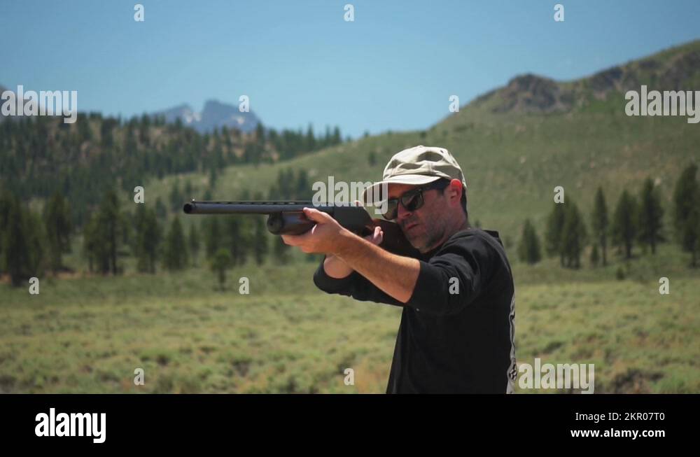 A male gunman shooting multiple shots with a pump action shotgun ...