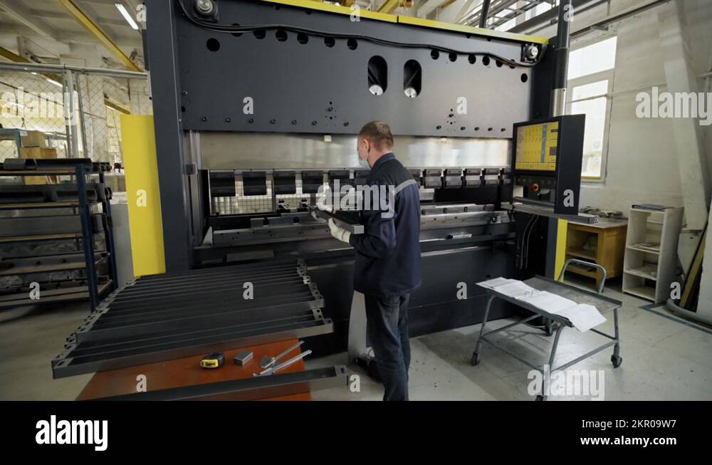 A Worker is placing a piece of metal under the CNC bending machine at a ...