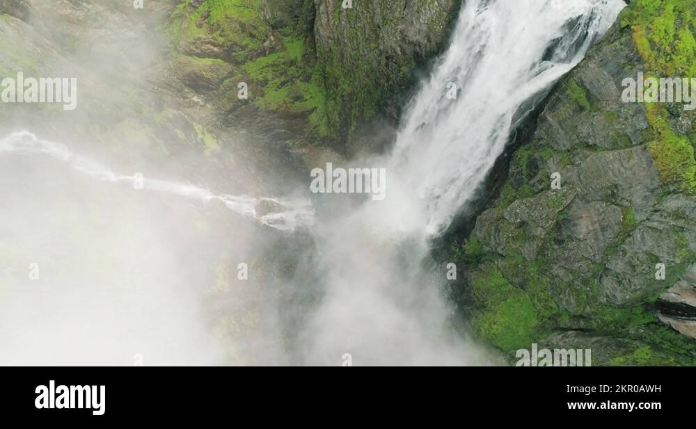 Dramatic Vøringsfossen waterfall rush splash down rocky foggy canyon ...