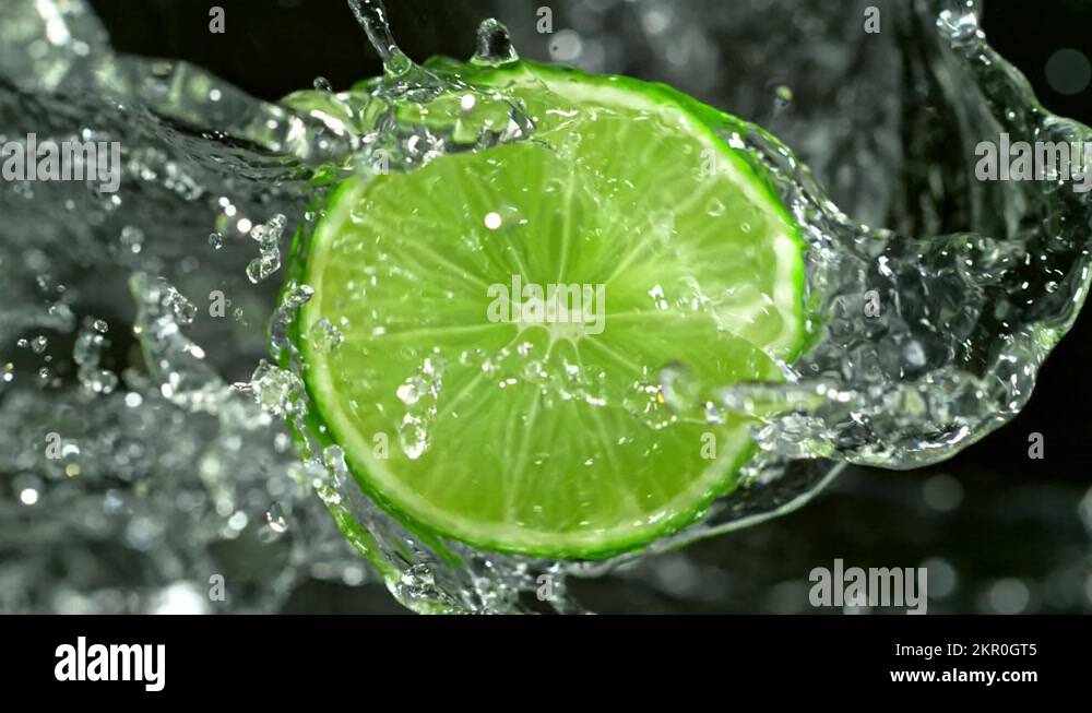Super Slow Motion Shot of Rotating Fresh Lime Slice and Splashing Water ...