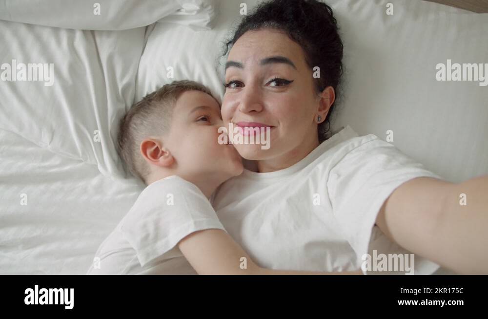 Portrait Happy Cute Funny Mom And Son Kiss Their Mom On Cheek Gently