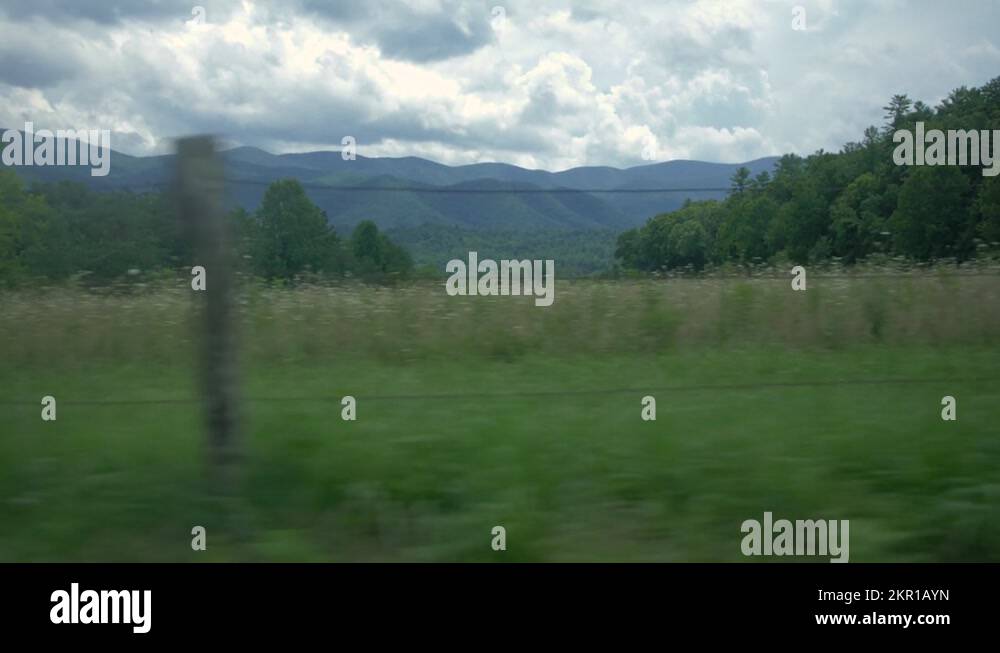 Driving by a stunning open valley with an old fence and mountains in ...