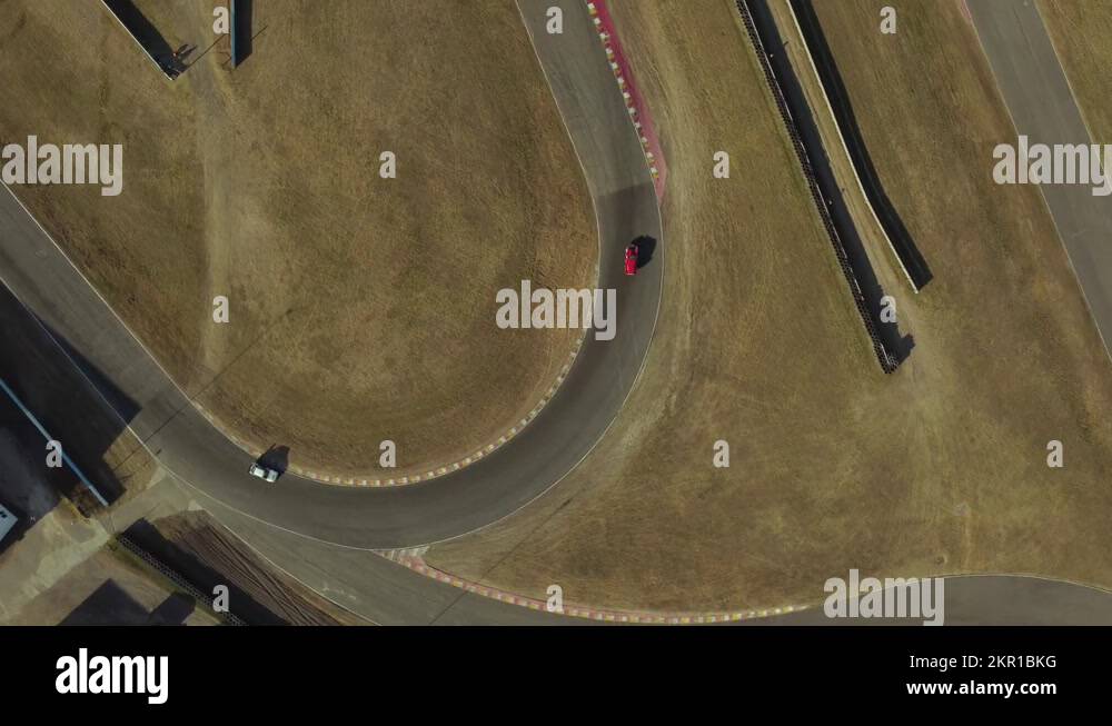 Rotational aerial view of racing cars turning at curve of racing track ...
