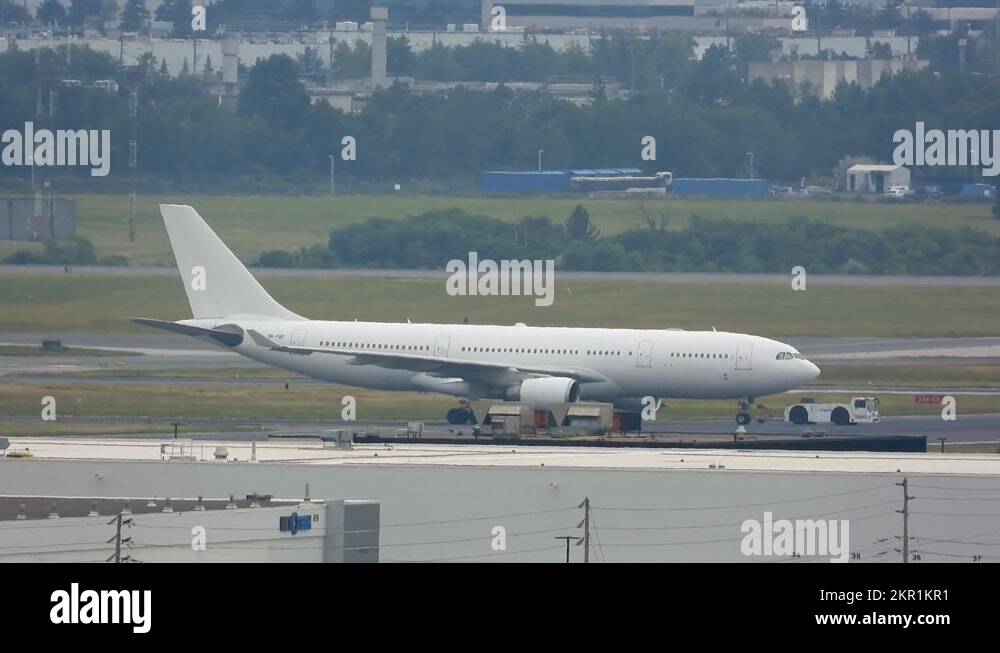 An unmarked Airbus A330 being pulled across an airport apron by a tug ...