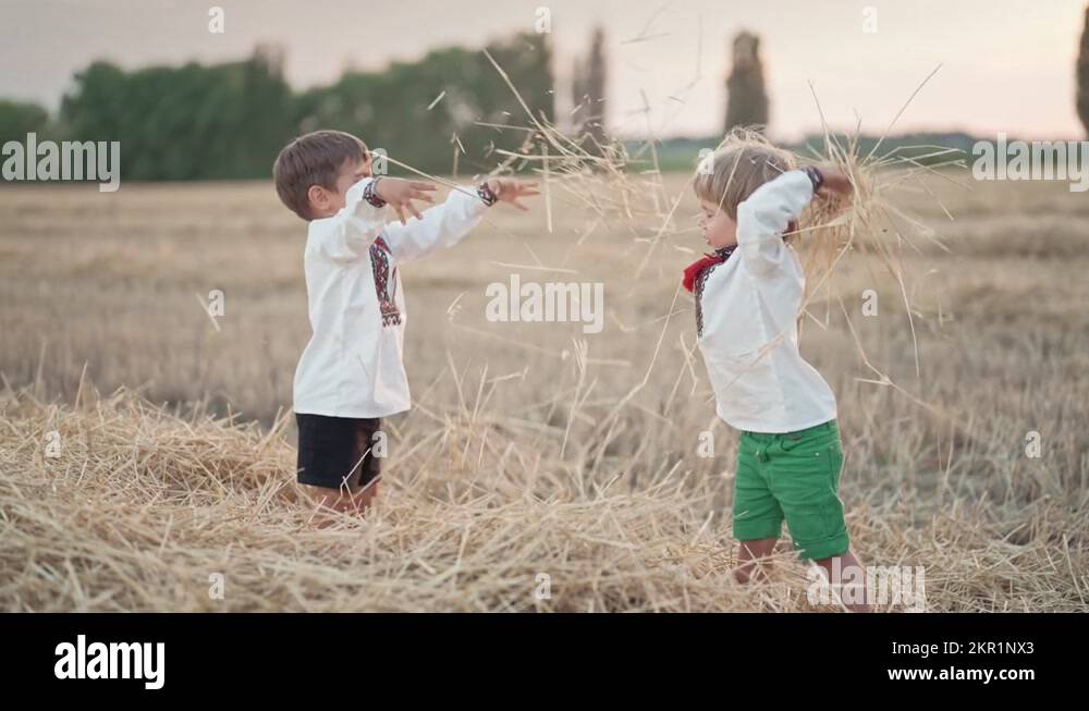 Little ukrainian children playing with hay, throw it up. Happy ...