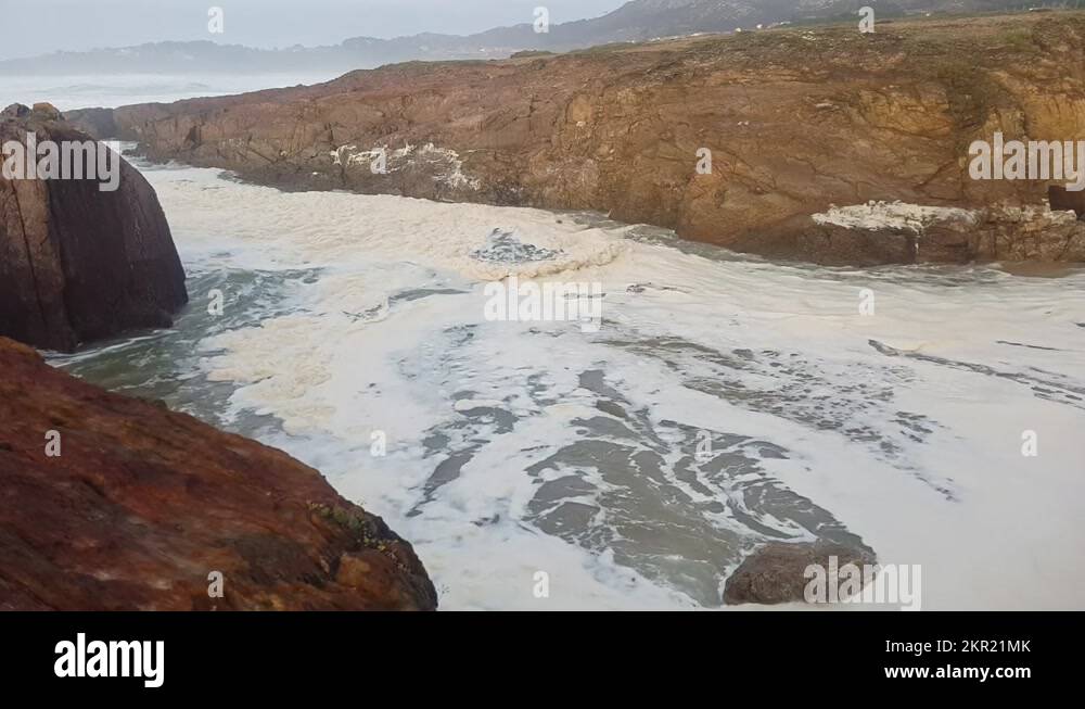 Wavy windy ocean sea, waves crashing against shore, polluted foam ...